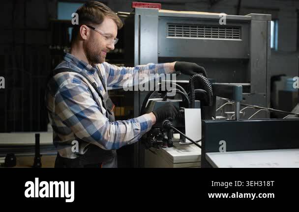 Male worker in a typography workshop setting up and operating an ...