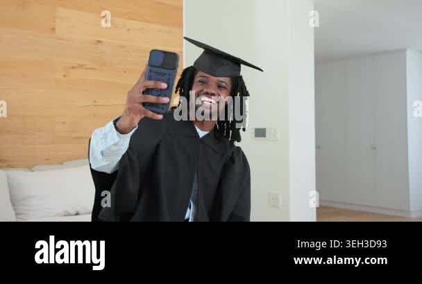 African male wearing gown and cap, celebrating grad while recording ...