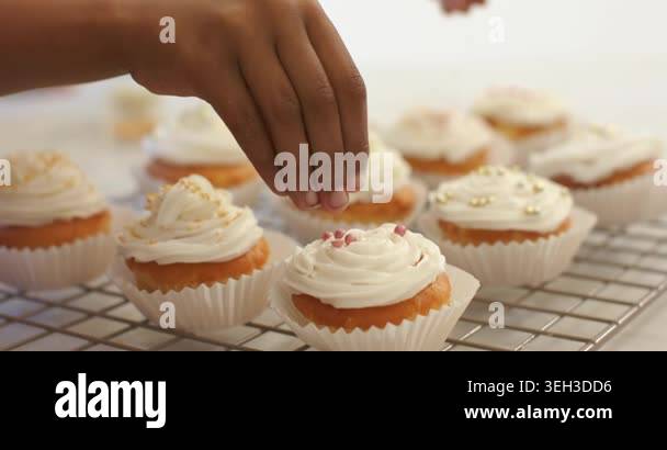 Hands entering left are scattering golden sprinkles and pink pearls on ...