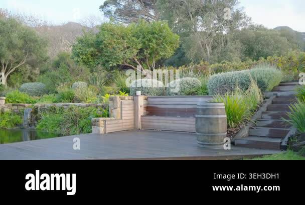 Camera is starting rightward pan from stone-edged pond to reveal wooden ...