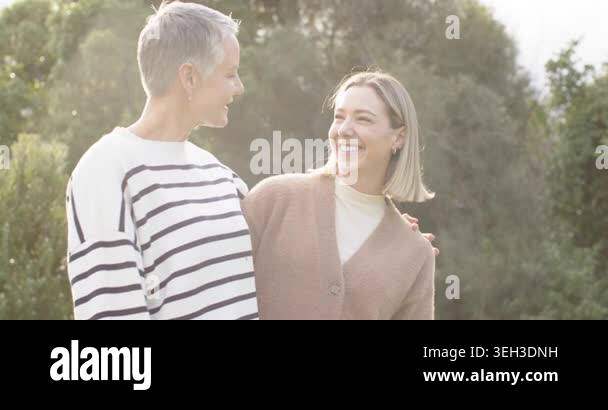 Mother and daughter smiling and laughing after mom slipping arm around ...