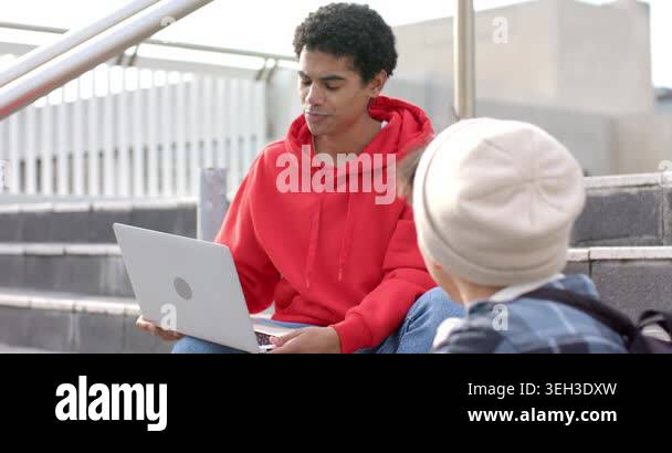 Male friends opening laptop and reviewing results while sharing ideas ...