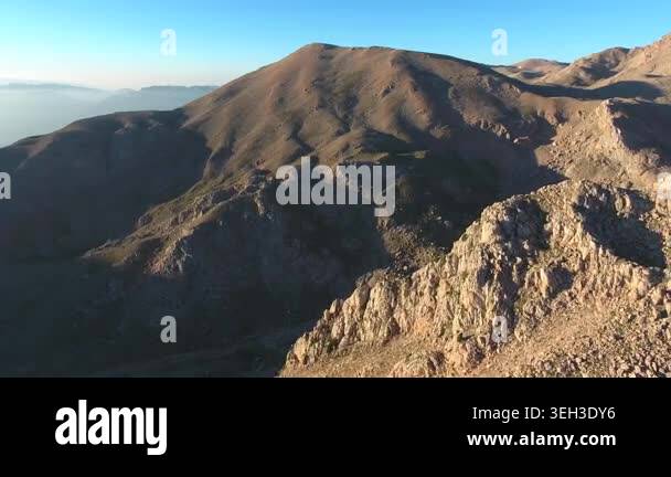 Aerial drone sunrise over barren mountain peaks touched by first ...