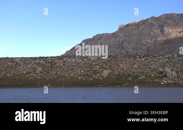 High altitude mountain lake beside treeless rocky hills with Ruddy ...