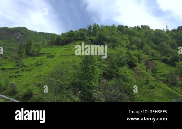 Wooden suspension bridge crossing wide flowing river within green rural ...