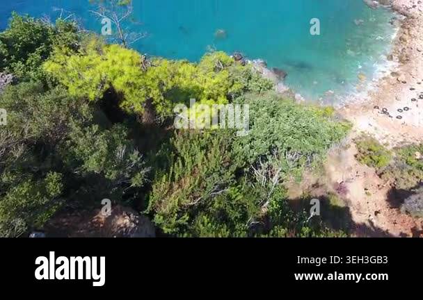Aerial drone view shows plastic trash and tires scattered along rocky ...
