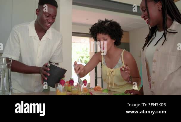 African American friends making drinks in kitchen yellow using tongs ...