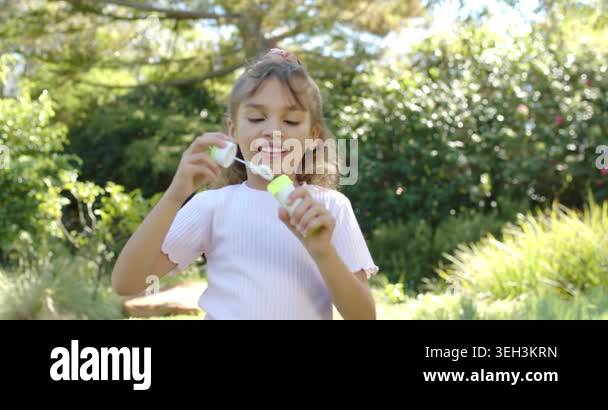 Opening bottle and dipping wand, African American child blowing and ...