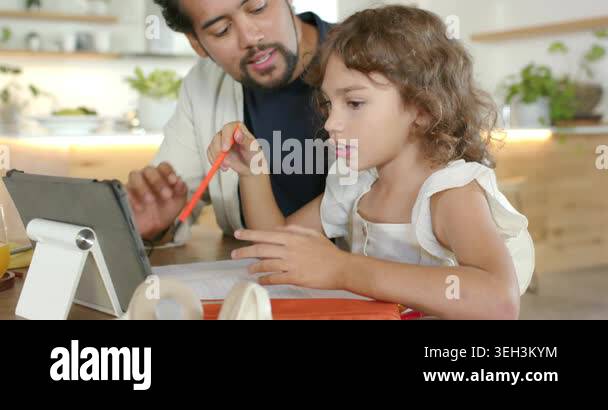 African American dad guiding child, pointing orange pencil at tablet ...