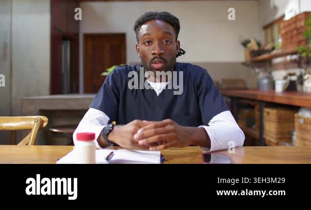 African American man in scrubs explaining medication, checking notes ...