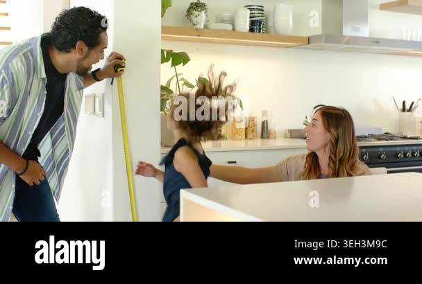 Parents and child measuring height father leaning with yellow tape on ...