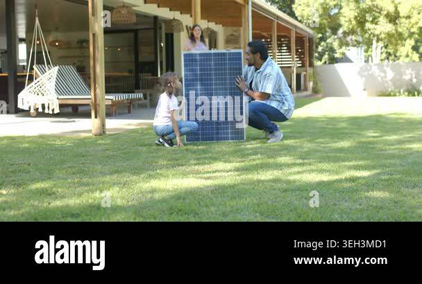 Diverse family steadying large solar panel needing support while ...