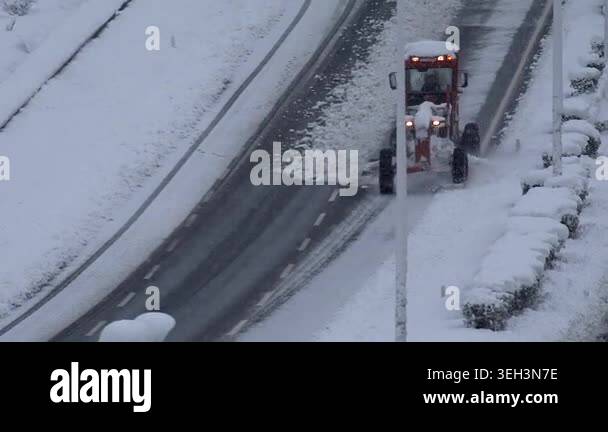 Snow removal vehicles clear a highway road during heavy winter weather ...