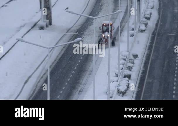Snow removal vehicles clear a highway road during heavy winter weather ...