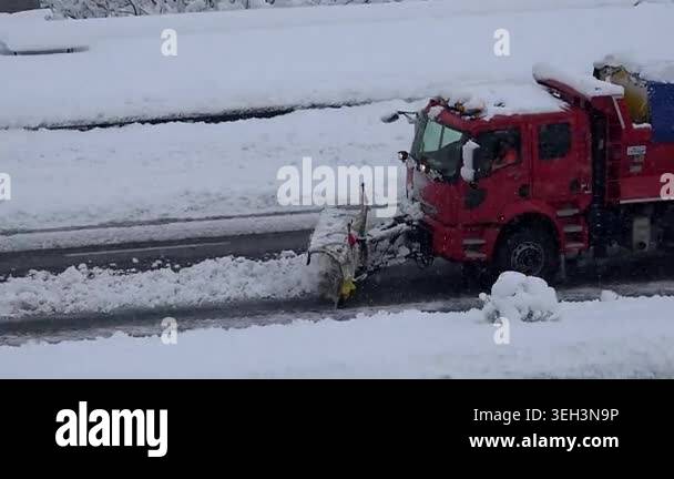 Snow removal vehicles clear a highway road during heavy winter weather ...