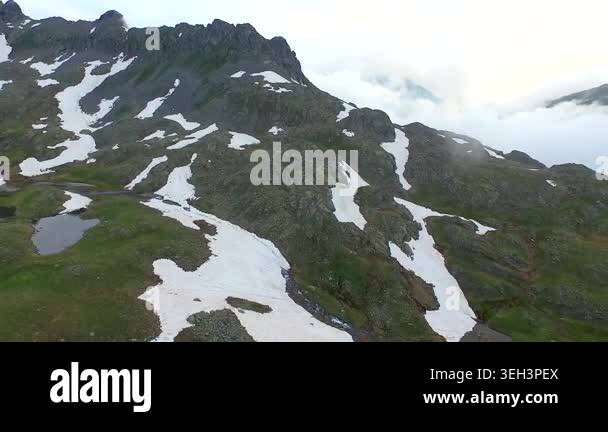 Aerial view of alpine mountain lake surrounded by melting spring snow ...