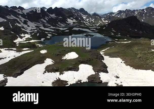 Aerial view of alpine mountain lake surrounded by melting spring snow ...