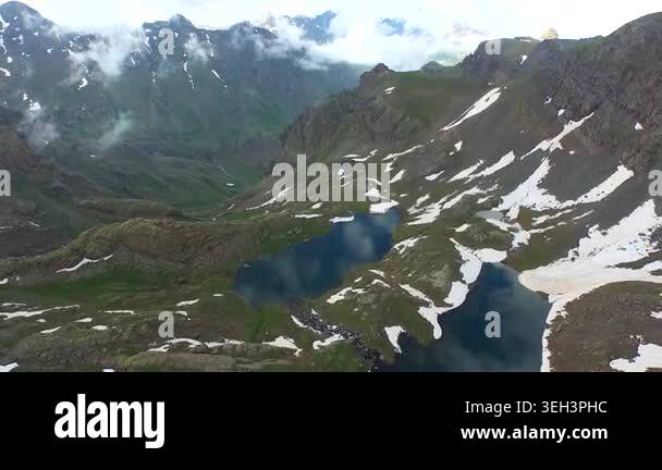 Aerial view of alpine mountain lake surrounded by melting spring snow ...