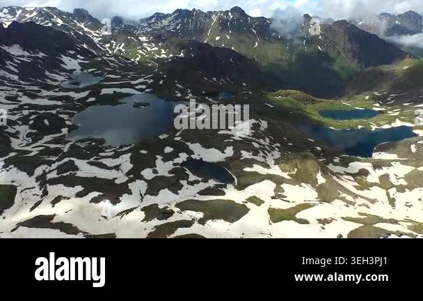 Aerial view of alpine mountain lake surrounded by melting spring snow ...