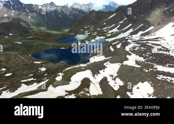 Aerial view of alpine mountain lake surrounded by melting spring snow ...