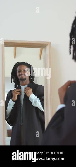 Vertical video: African man seeing self in mirror in room, adjusting ...