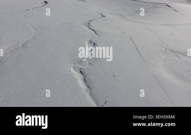 Aerial stream bed covered with thick pristine snow in treeless winter ...