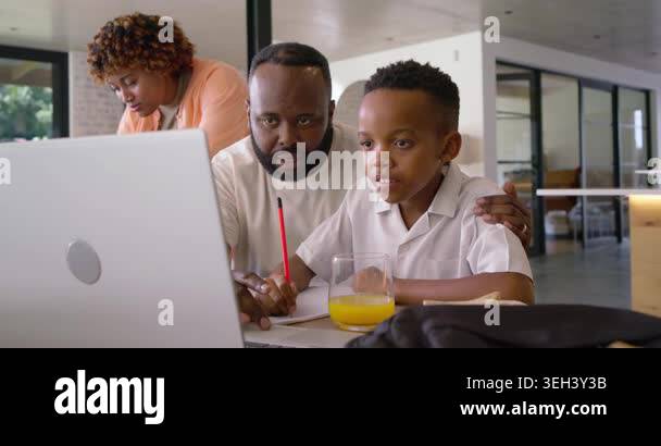 African family at table parents leaning pointing helping kids with ...