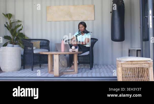 African American woman on patio checking laptop and starting podcast ...