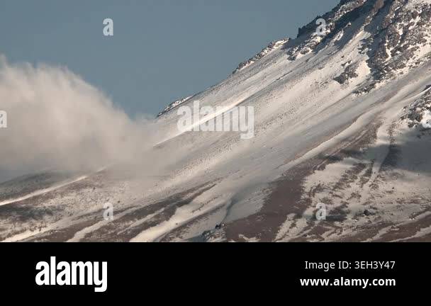 Smooth treeless sloping snowy mountain slope at cloud height with ...