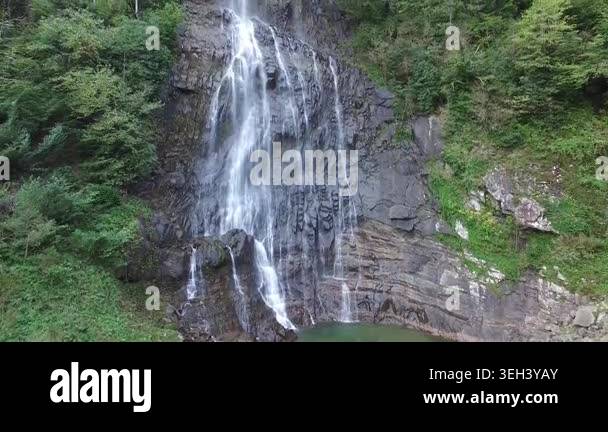 Aerial drone view captures a high waterfall flowing from a towering ...