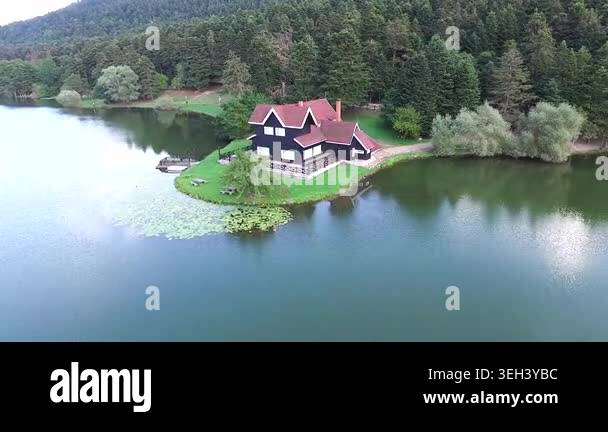 Aerial drone view of a serene forest cabin by a lakeside in natural ...