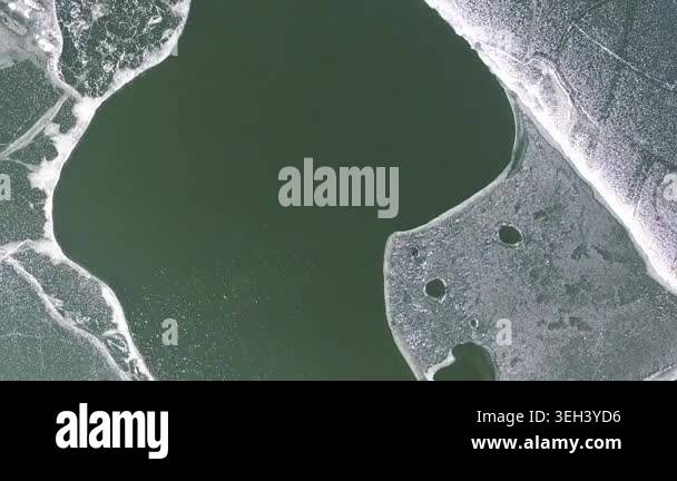 Aerial view of frozen lake surface with thick ice layer and cracks in a ...