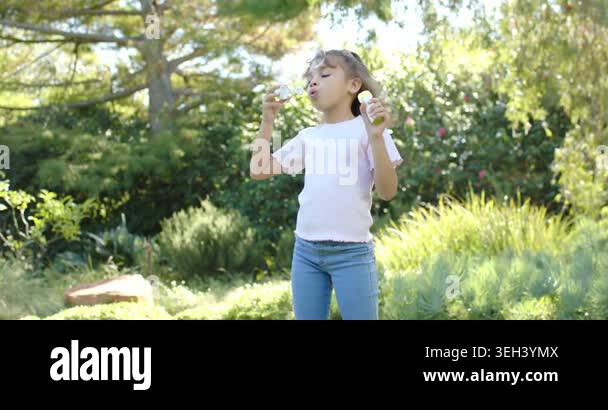 Puckering, lifting wand, African-American child blowing bubbles in ...