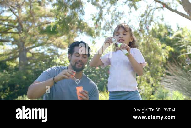 African American father teaching child dipping wand in orange bottle ...