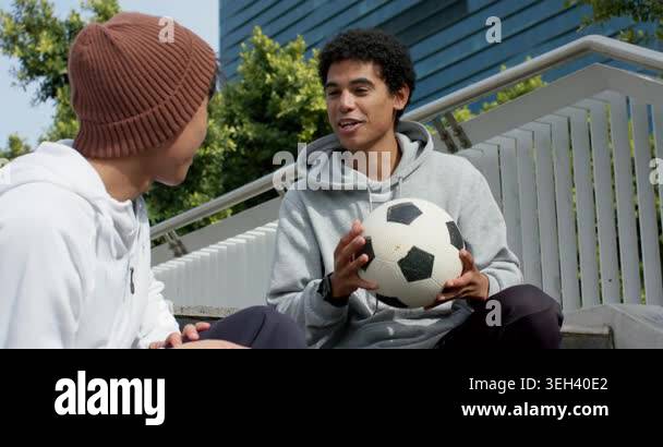 Diverse male friends holding soccer ball sharing animated story on ...