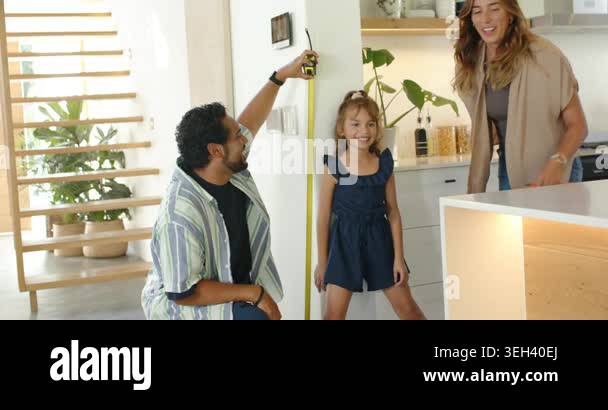 Family father kneeling extending yellow tape, measuring youth girl ...
