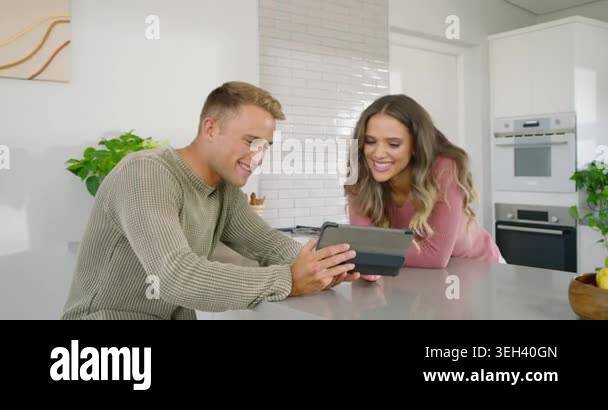 Diverse couple leaning at kitchen island, woman pointing, man tapping ...