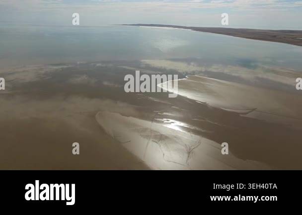 Aerial view of Aral lake over sandy shoreline with shallow calm water ...