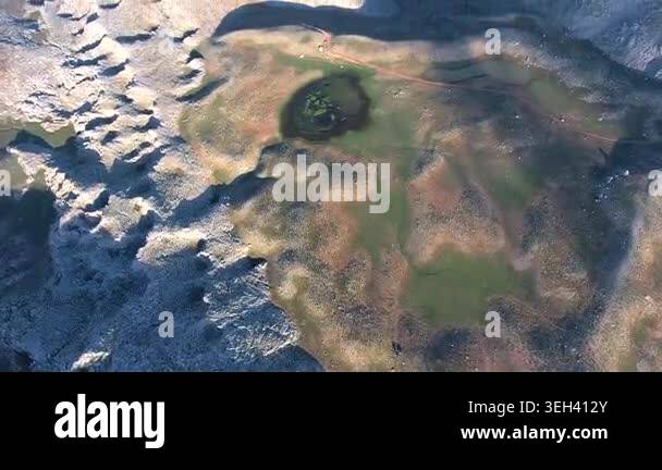 Mountain lake meets barren plateau in Ladakh, with rocky slopes and ...