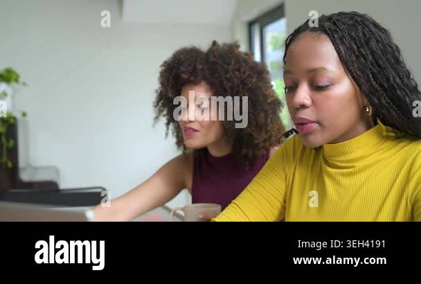 Diverse female coworkers leaning in discussing design layouts and using ...