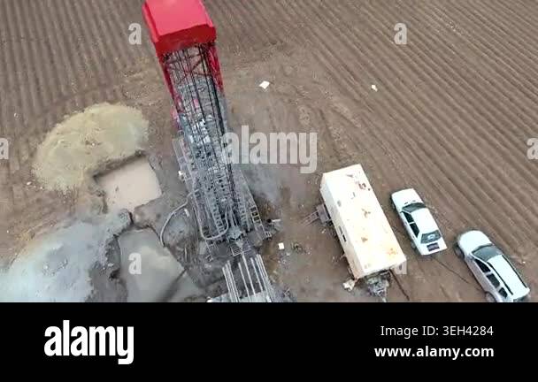Aerial view shows water well drilling rig working farmland for artesian ...