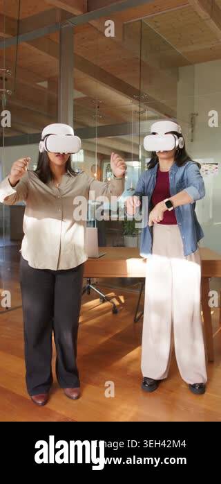 Vertical video: Two Asian women on VR demo in office wearing white ...