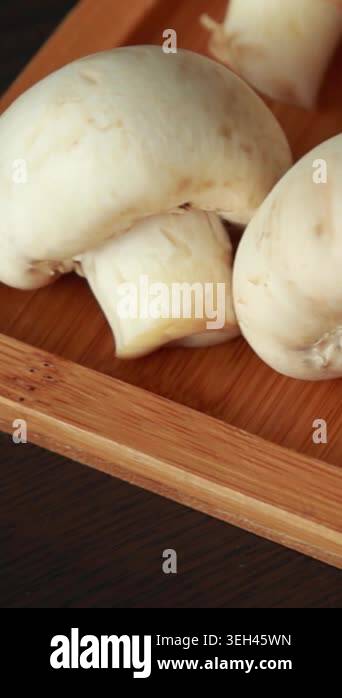 Vertical video close-up of fresh, raw white champignon mushrooms neatly ...