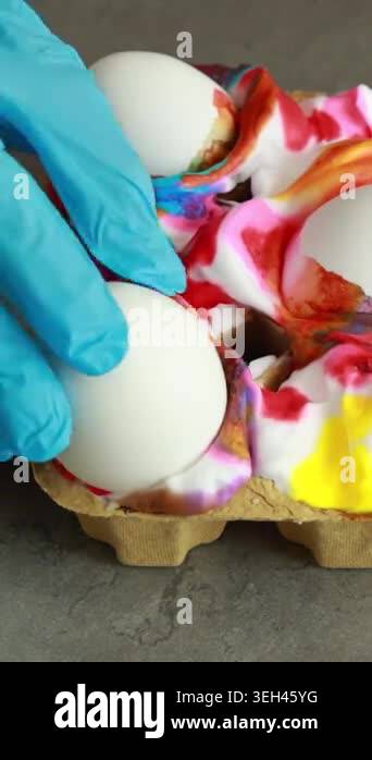 Vertical video close-up of a child's hands decorating Easter eggs using ...