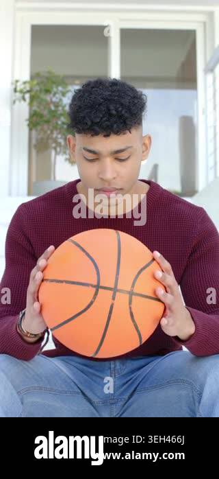 Vertical video: African American male placing ball at home, dribbling ...