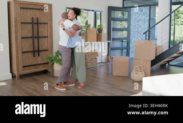 African American couple moving in, unpacking boxes in entryway, hugging ...