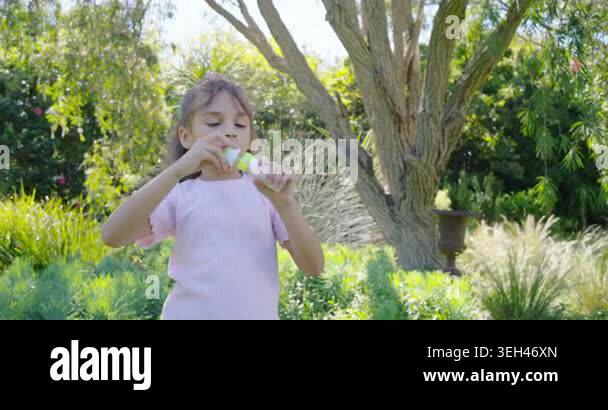 Girl child unscrewing bubble cap, dipping wand and blowing bubbles ...