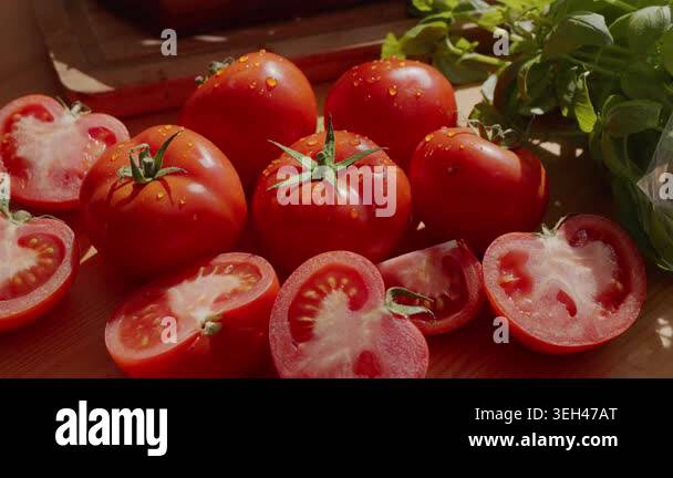 Fresh organic red tomatoes and slices with green leaves on a sunny ...