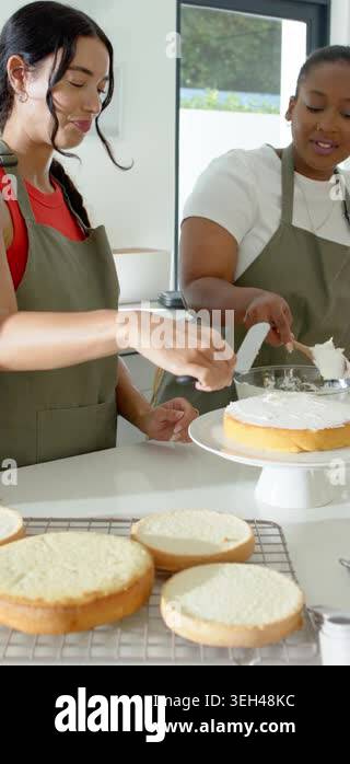 Vertical video: Diverse female bakers selecting layer and smoothing ...