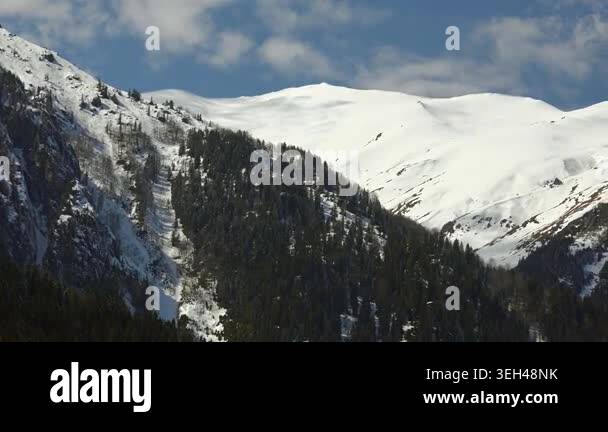 Ural Mountains snowy peaks above pine forest valley under blue sky ...